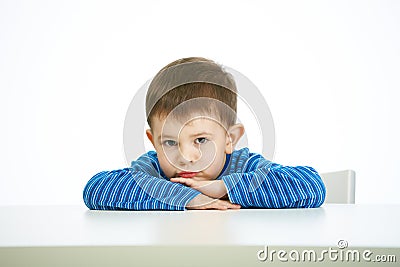 Portrait Of Sullen Little Boy Sitting At Table Royalty-Free Stock ...