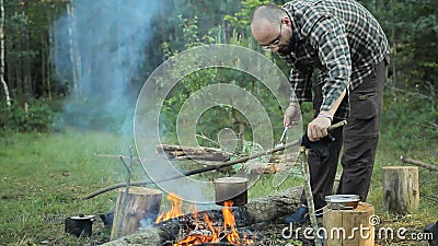 In a Pot on the Fire Boiling Water. a Man Removes Scum and Throws Away ...