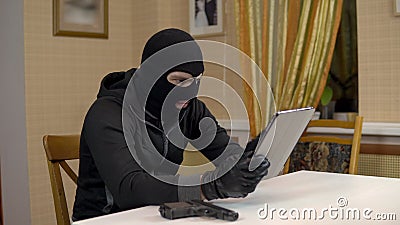 A Robber is Trying To Hack into a Tablet. a Masked Thug is Sitting in a ...