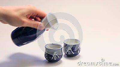 Pouring Sake from a Big Sake Bottle into Small Round Ceramic Sake Cup ...