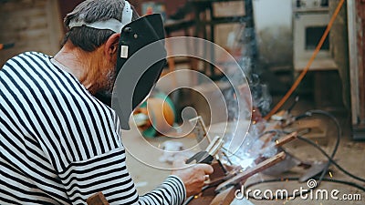 Side View of Person in a Welding Helmet Welds Metal Products on the ...