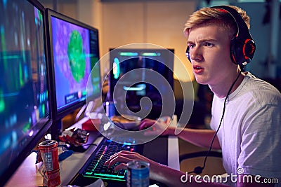 Teenage Boy Wearing Headset Gaming At Home Using Dual Computer Screens ...