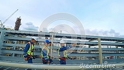 Three Engineers in Hardhat are Moving through a Heavy Industry Factory ...