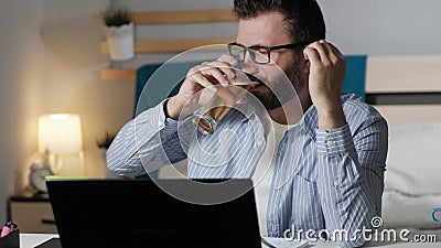 Tired Man Works at Computer Writes Notes in Notebook and Drinking Beer ...