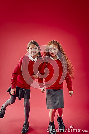 Two Elementary School Pupils Wearing Uniform Linking Arms Against Red ...