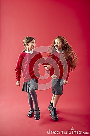 Two Elementary School Pupils Wearing Uniform Linking Arms Against Red ...