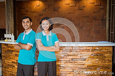 Two Receptionists Standing With Hands Crossed Against Reception Desk ...