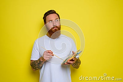 Undecided Man With Beard And Tattoo Is Ready To Draw With Brushes ...