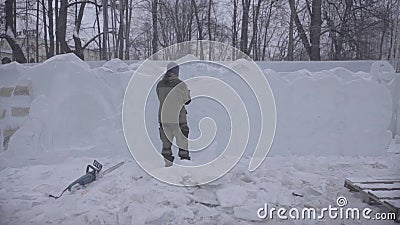 Worker Using a Chainsaw Carving an Ice Sculpture. Men Discuss Work with ...