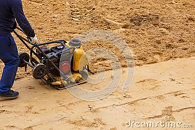 Worker Using Vibratory Plate Compactor For Compaction Sand During Path ...