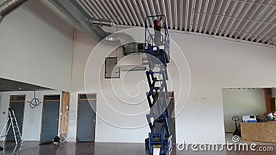 A Working Man on Scissor Lift Fixing Ceiling. Construction Work Concept ...