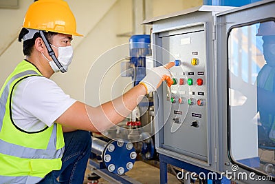 Young Electrical Engineer Wearing A Mask Inspect The Electrical Control ...