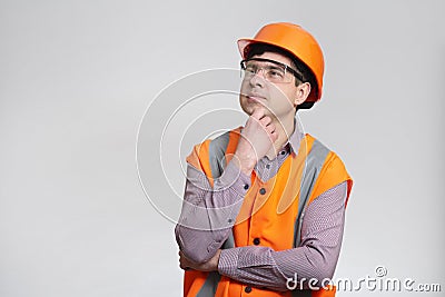 Young Engineer In Hard Hat And Reflective Vest Thinking On Grey Studio ...