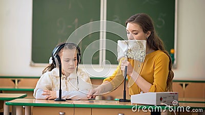 Young Girl and Teacher Using Headphones and Microphone in the Classroom ...