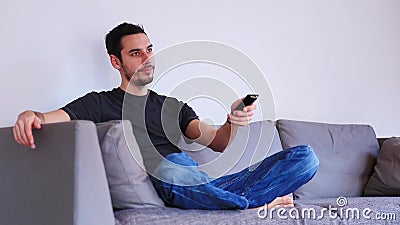 Man Sitting on Sofa and Watching TV Using Remote Control Stock Video ...