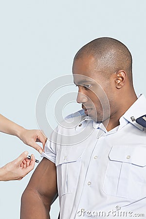 Young Military Man Getting An Injection From Nurse Over Light Blue ...