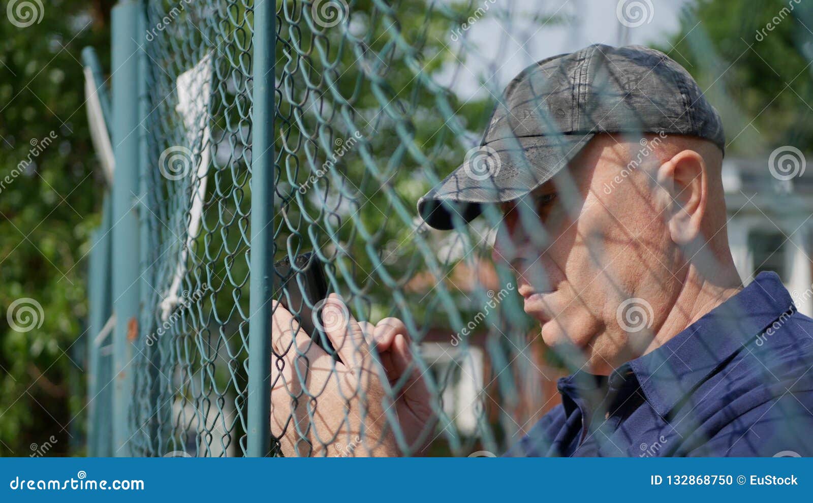 Man Near a Metallic Fence Text Using a Smartphone. Stock Photo - Image ...