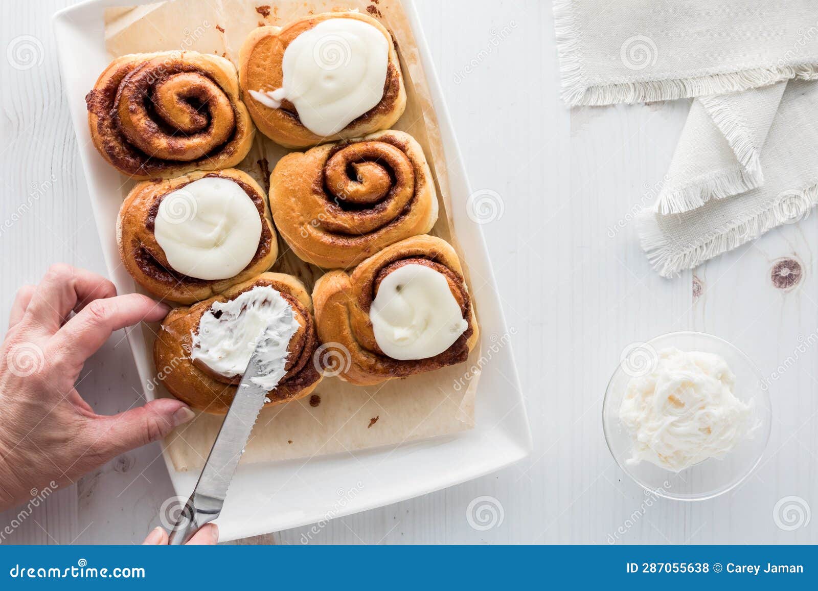 Hands Spreading Vanilla Frosting on a Cinnamon Bun. Stock Photo - Image ...