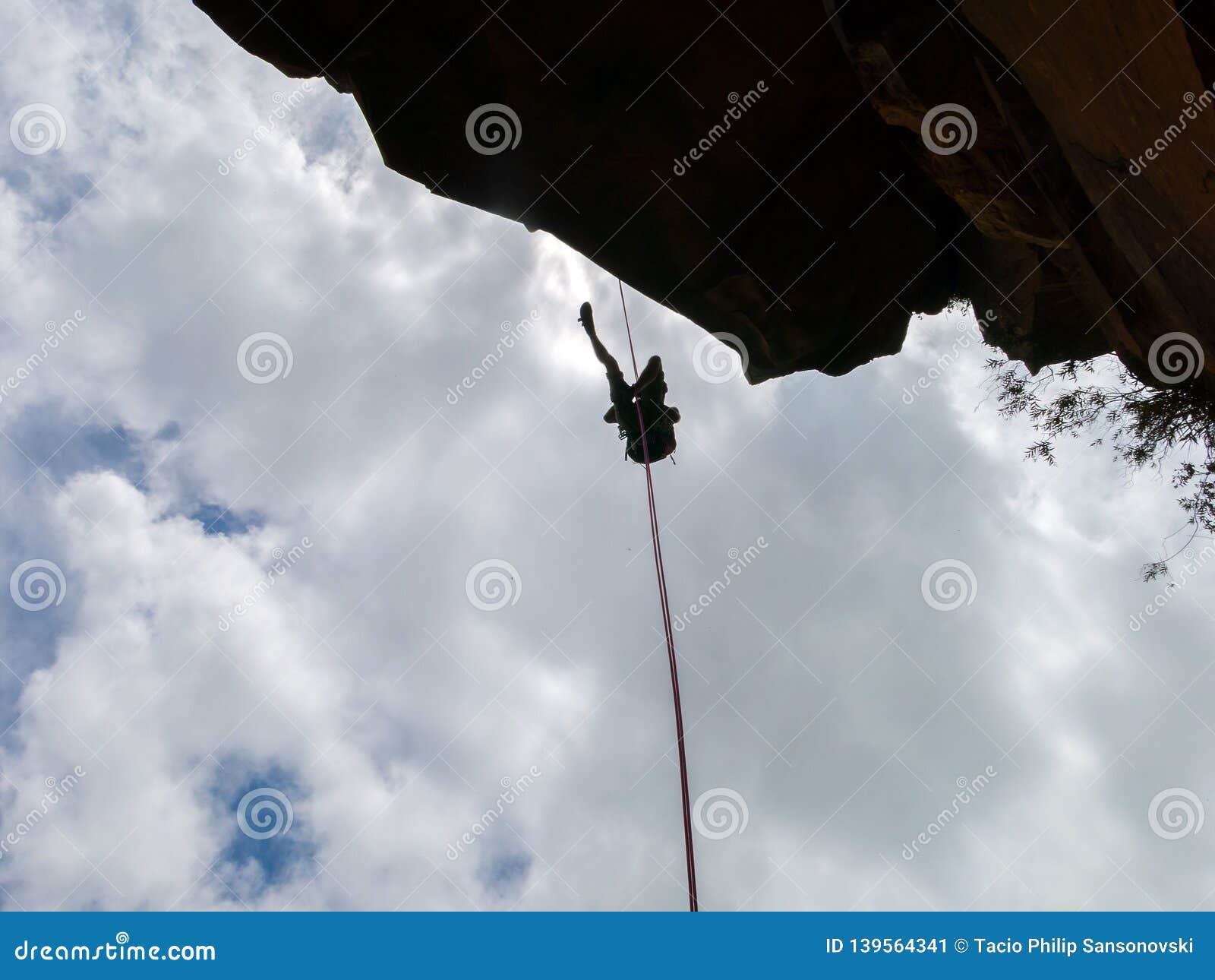 Abseiling a Negative Sanstone Rock Wall with Blue Sky on Background ...