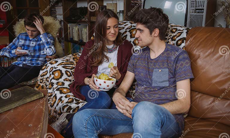 Acople Comer Microplaquetas Em Uma Vista Do Sofá E Do Amigo Imagem de Stock - Imagem de grupo ...