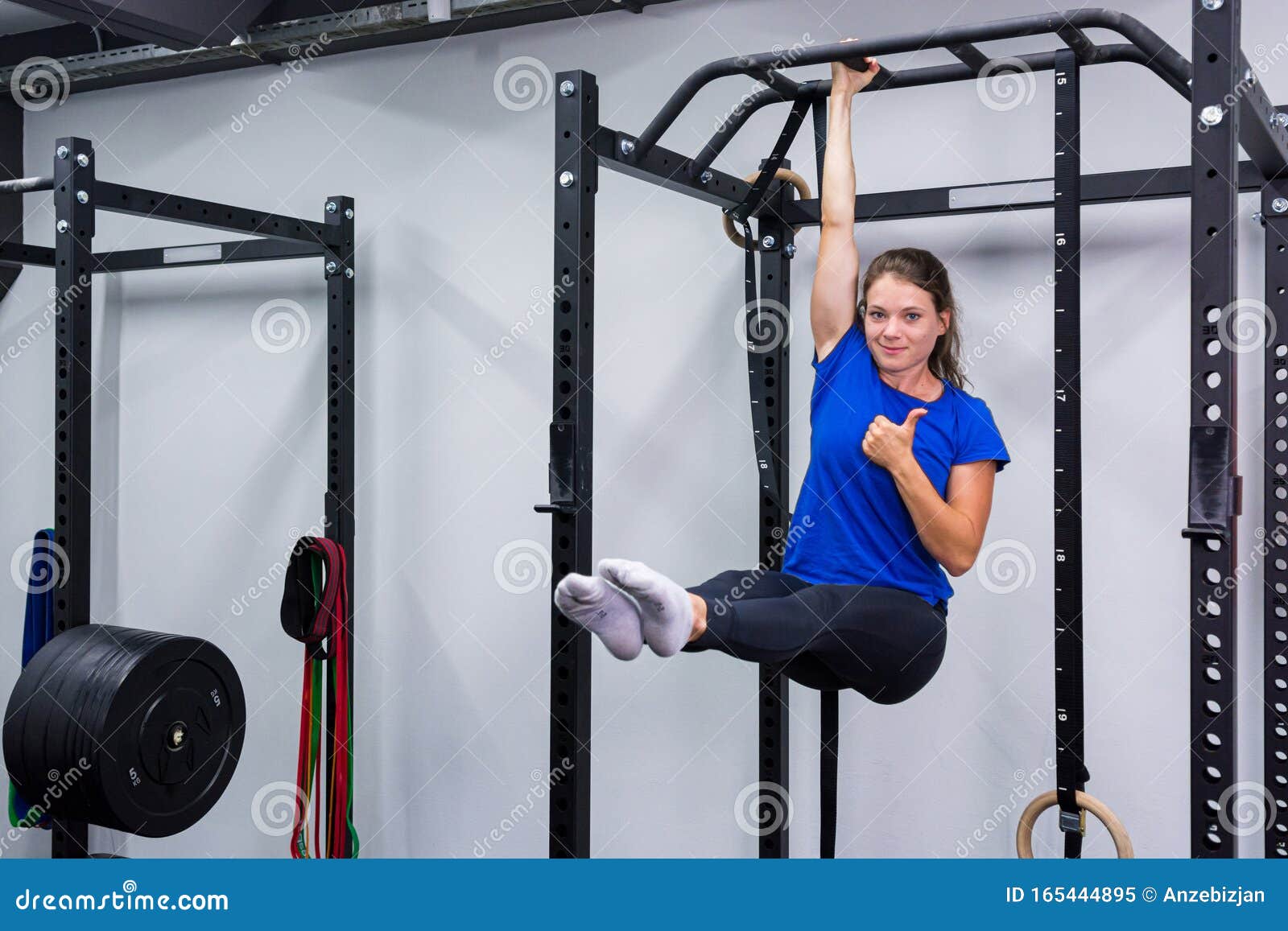 Active Brunette Having Fun on Pullup Rig Doing One Hand Leg-raises ...