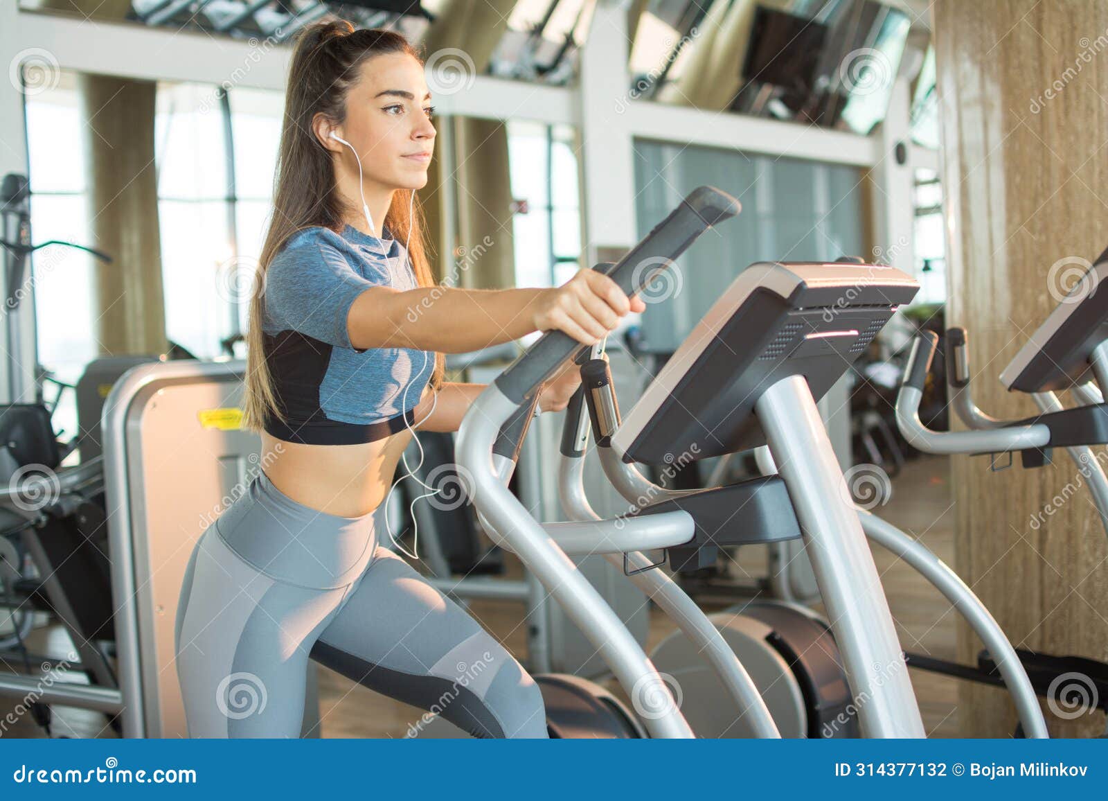 Active Young Woman Exercising on Elliptical Trainer Machine at Gym ...