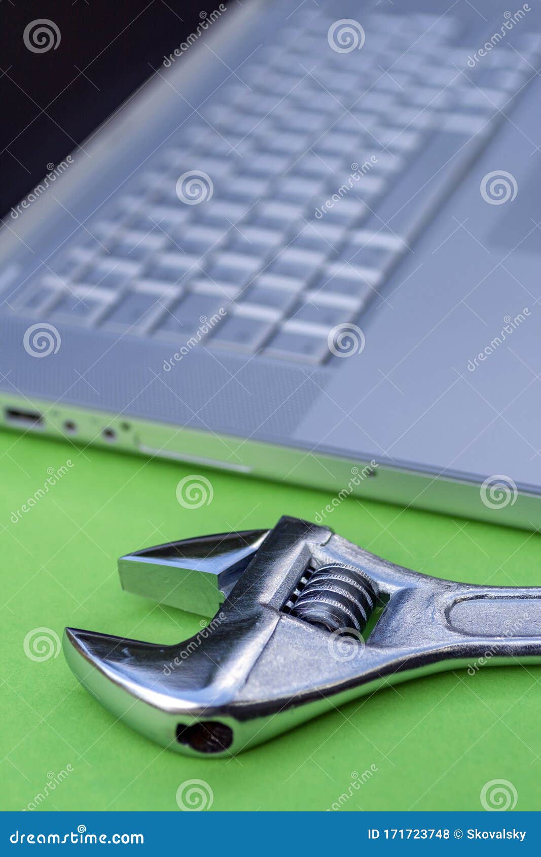 Adjustable Wrench Next To a Silver Laptop. Computer Service ...