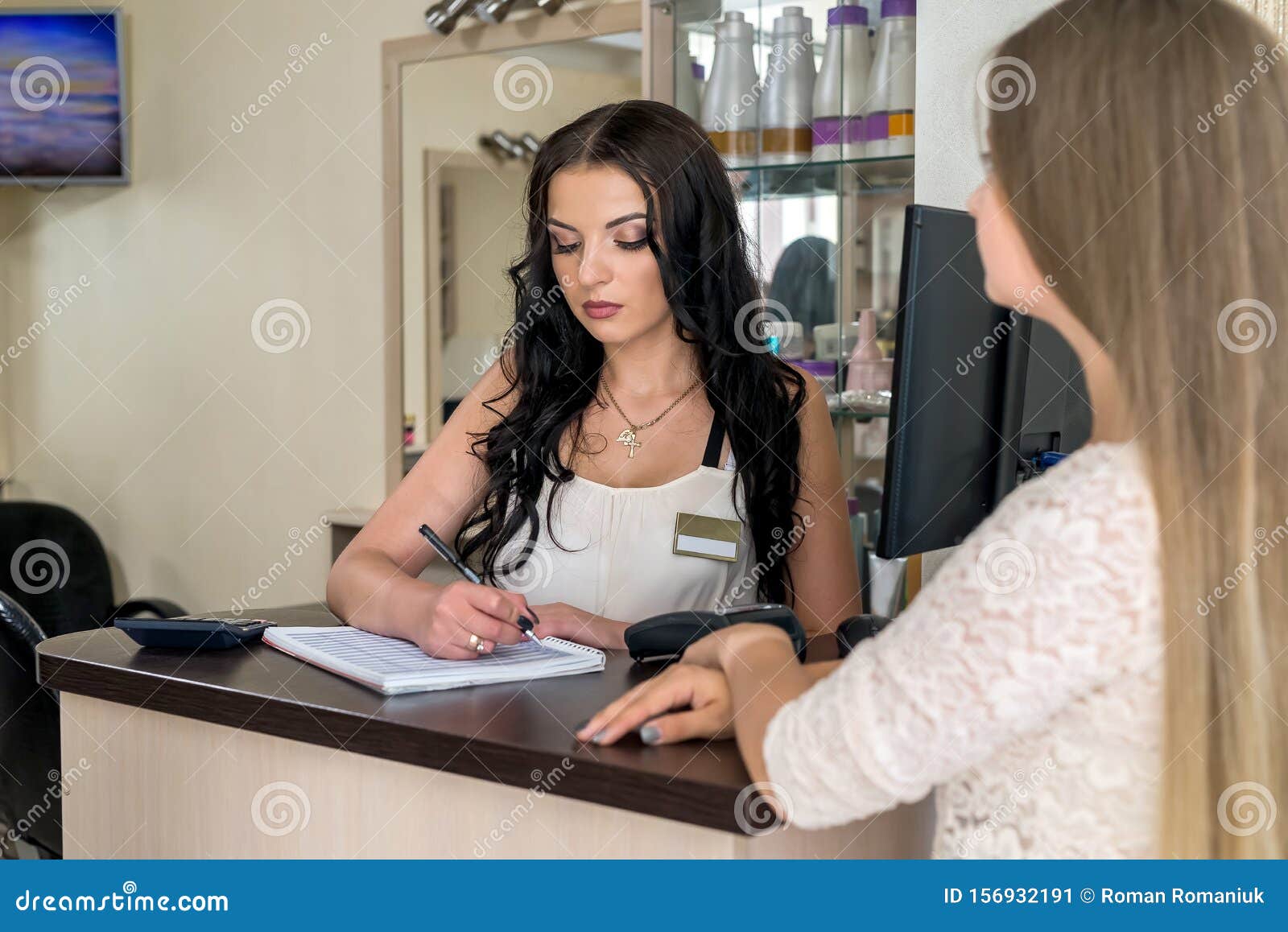Administrator and Client at Reception Table Making Note To Schedule ...