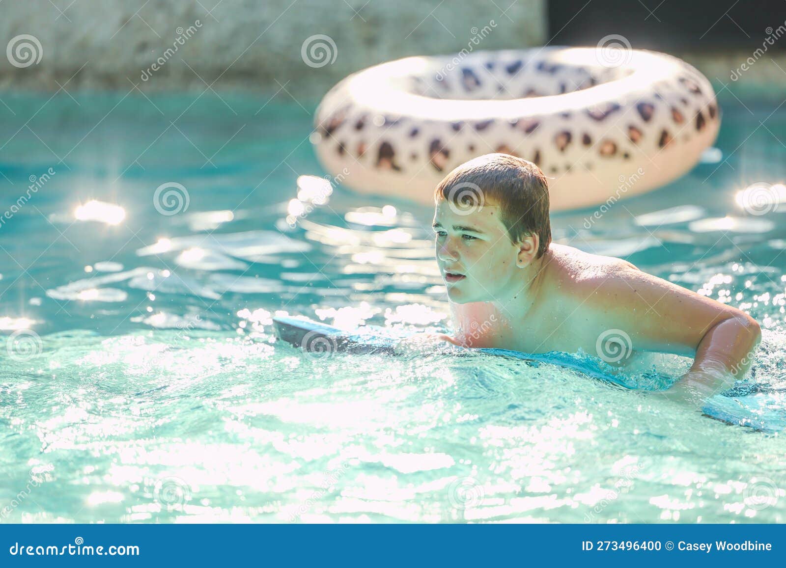 Adolescent Boy Swimming on Boogie Board in Backyard Pool in the Summer ...