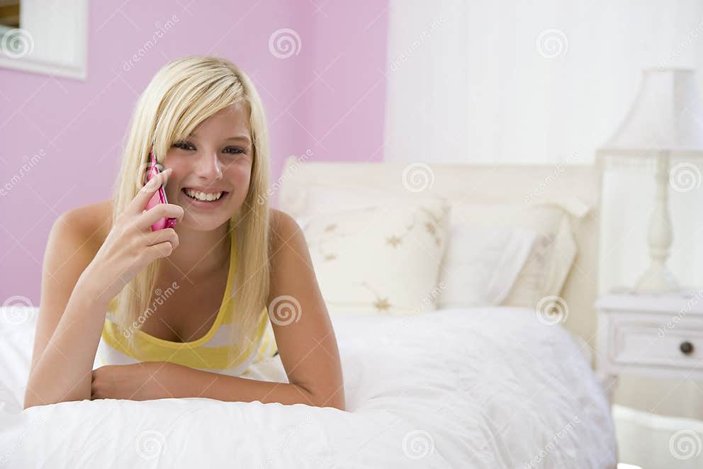 Adolescente Que Miente En Cama Usando El Teléfono Móvil Foto De Archivo