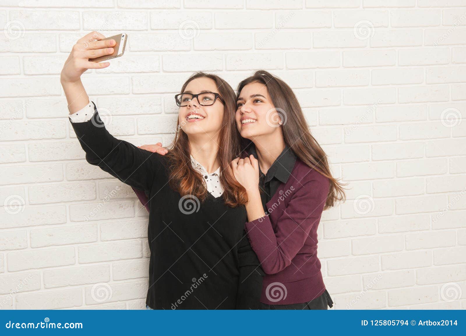 Adolescentes De Las Muchachas Contra Una Pared De Ladrillo Blanca Foto