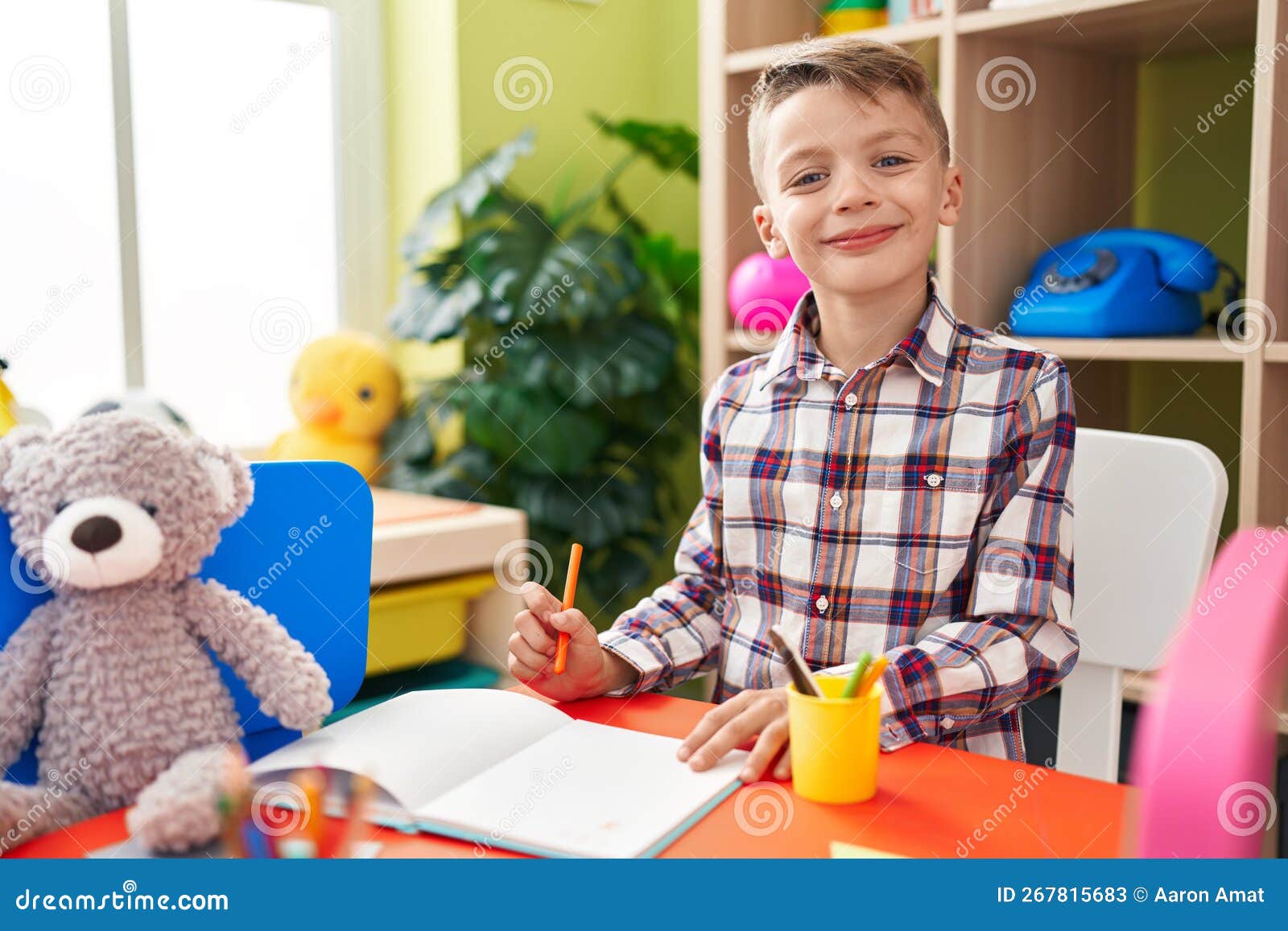 Adorable Caucasian Boy Student Sitting on Table Drawing on Notebook at ...