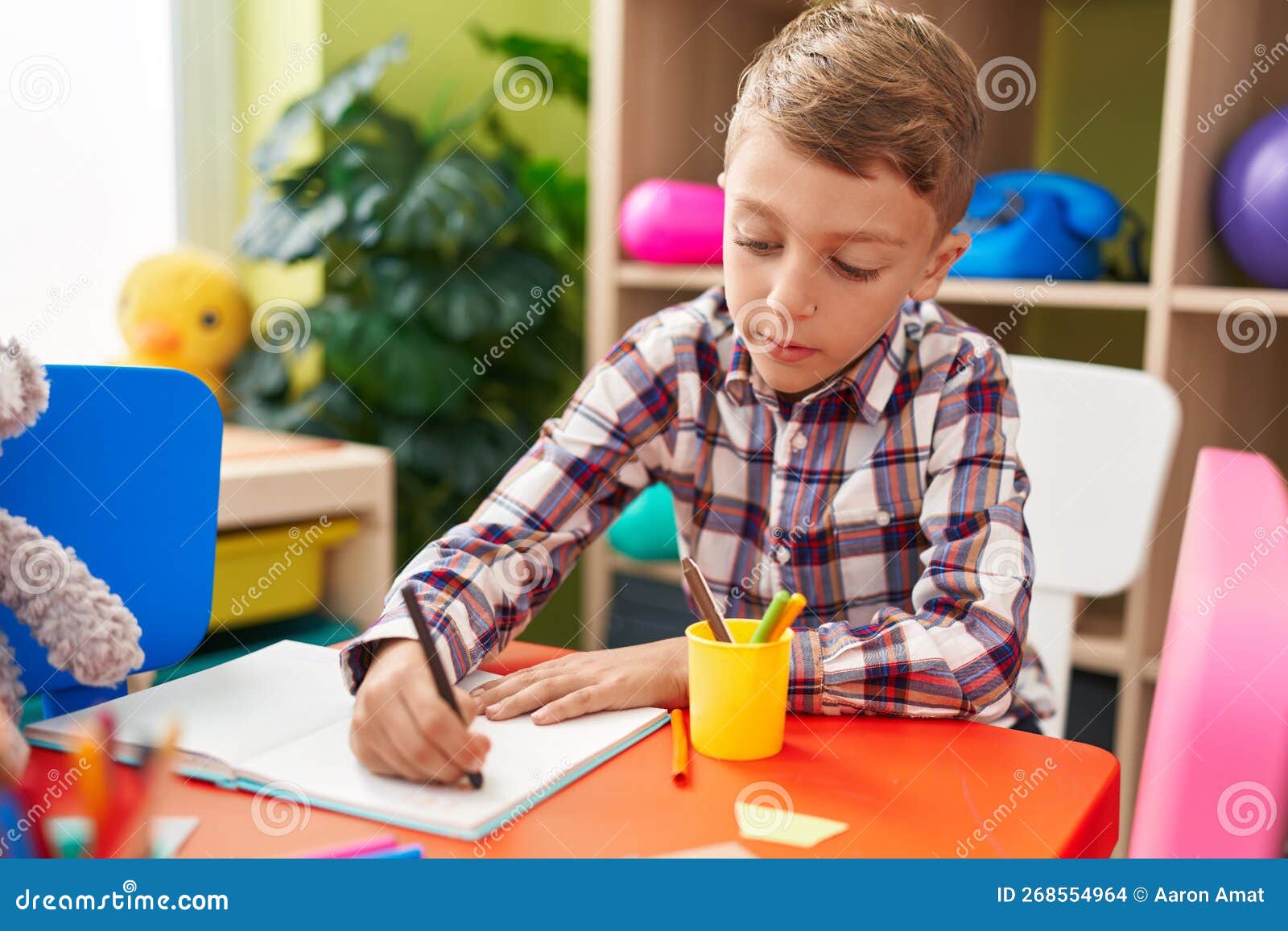 Adorable Caucasian Boy Student Sitting on Table Drawing on Notebook at ...