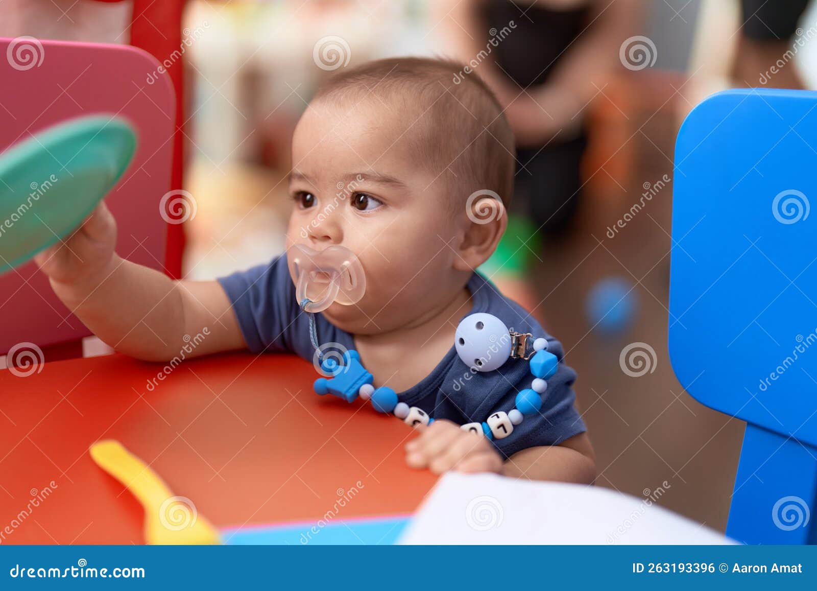 Adorable Chinese Toddler Using Pacifier Holding Dish Toy at ...