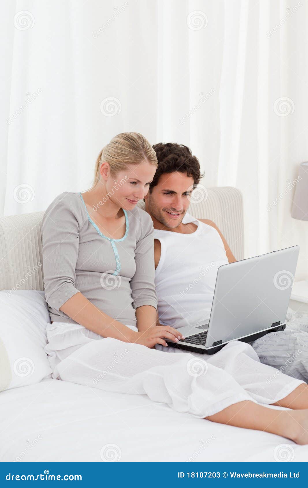 Adorable Couple Looking at Their Laptop on the Bed Stock Image - Image ...