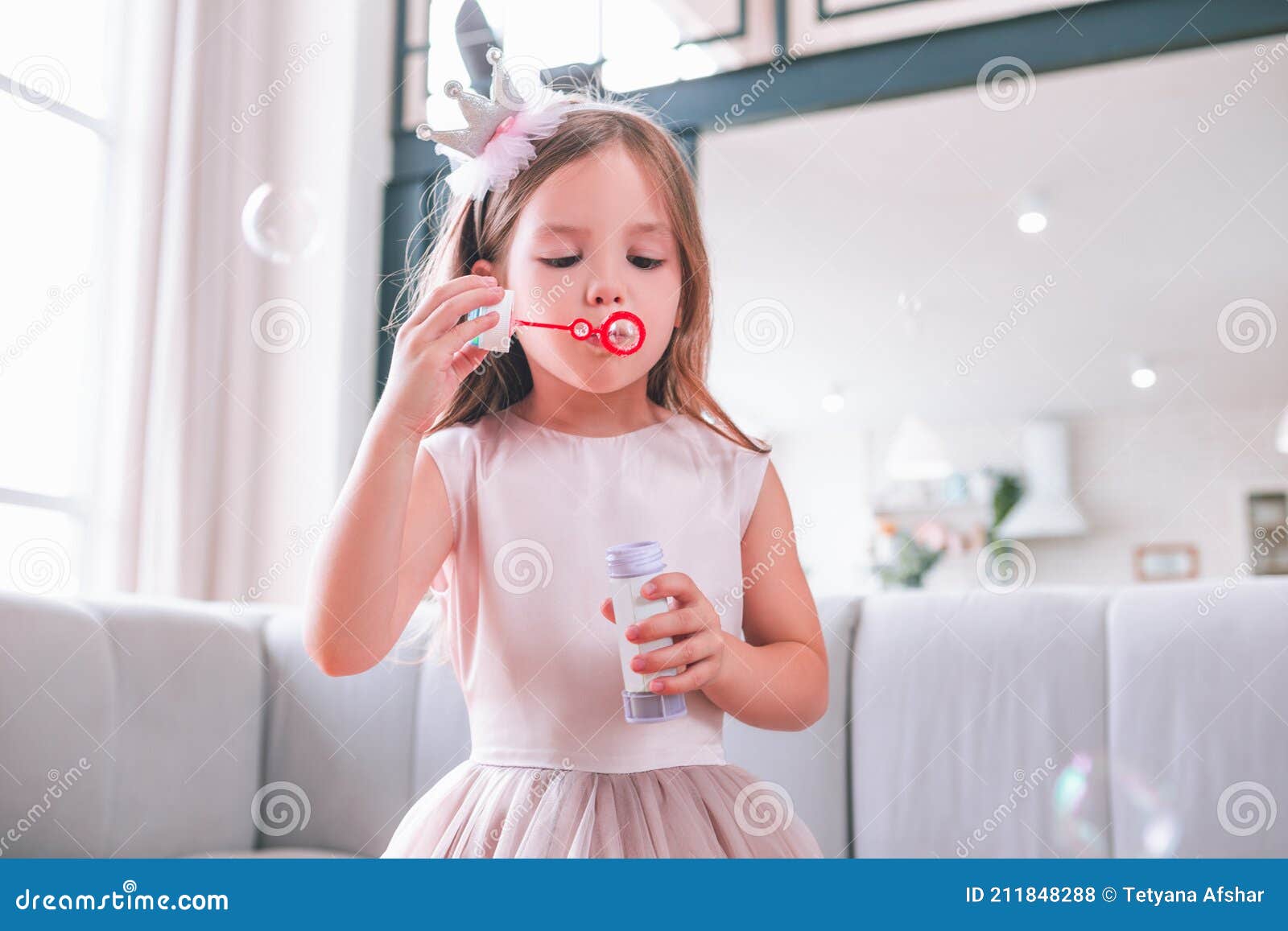 Adorable Fille Soufflant Des Bulles De Savon Dans Le Salon Photo Stock