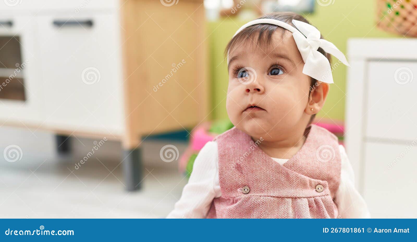 Adorable Hispanic Baby Sitting on Floor with Relaxed Expression at ...