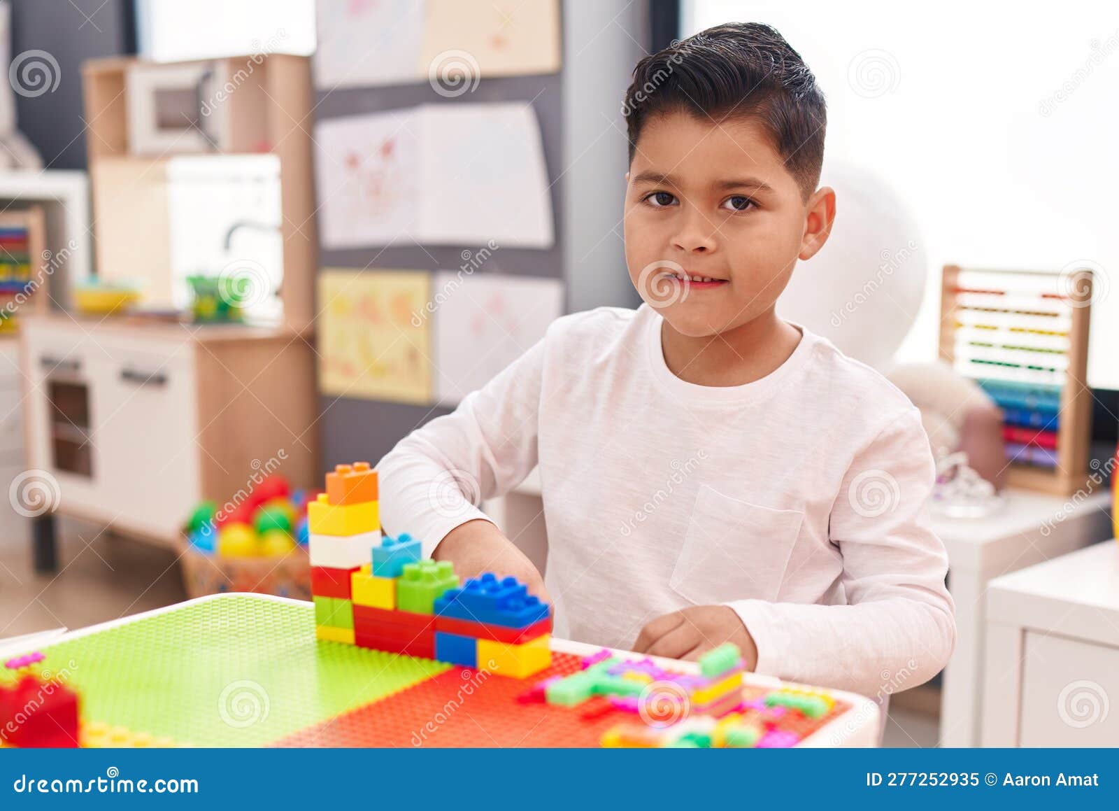 Adorable Hispanic Boy Playing with Construction Blocks Sitting on Table at Kindergarten Stock ...