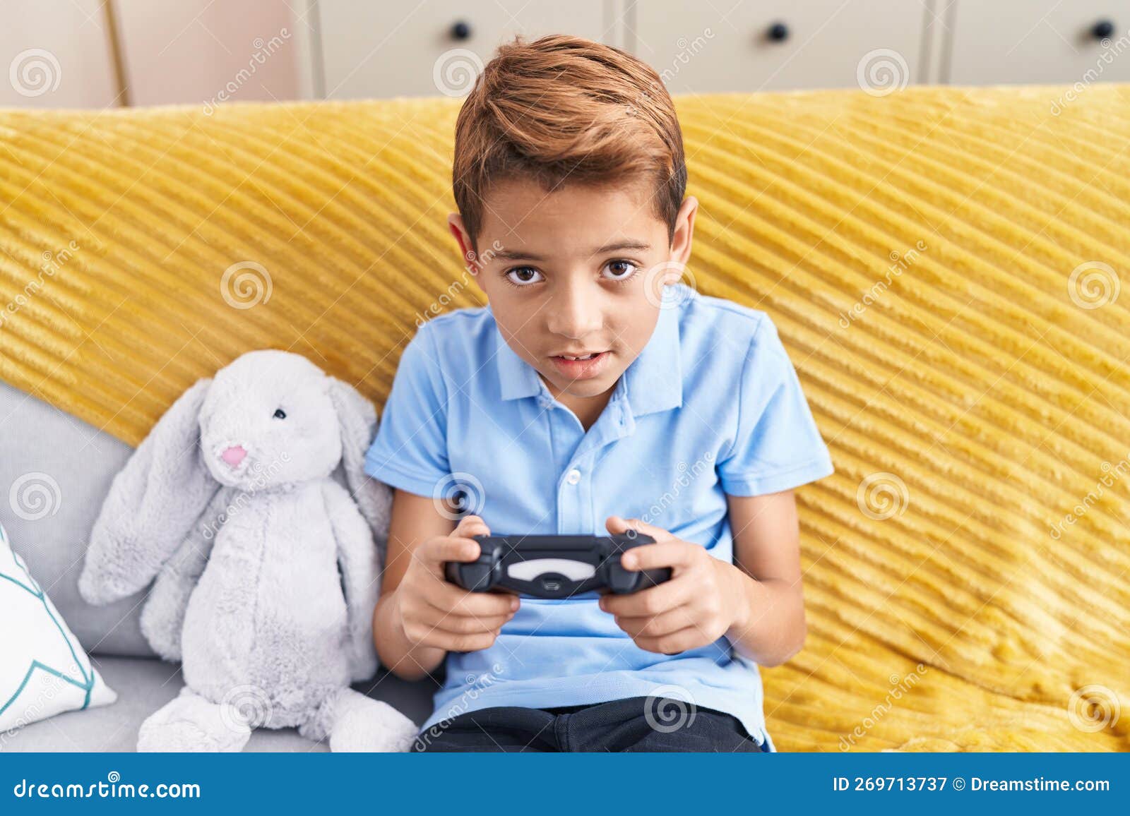 Adorable Hispanic Boy Playing Video Game Sitting on Sofa at Home Stock ...