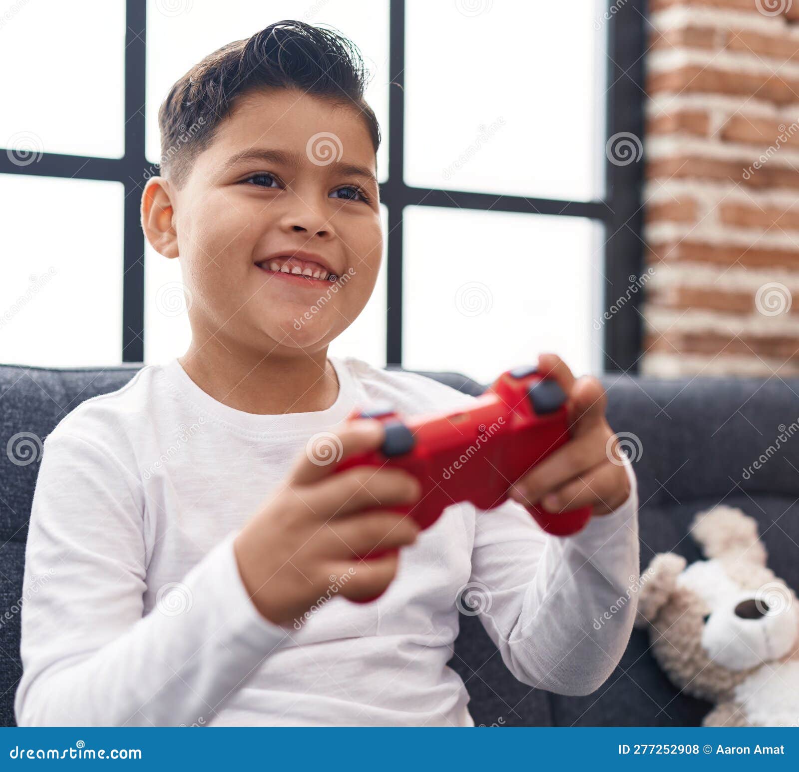 Adorable Hispanic Boy Playing Video Game Sitting on Sofa at Home Stock ...