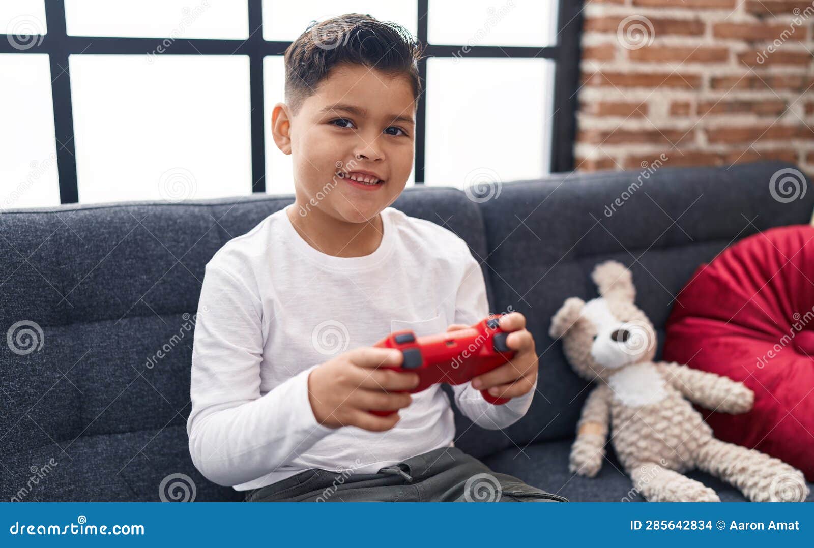 Adorable Hispanic Boy Playing Video Game Sitting on Sofa at Home Stock ...