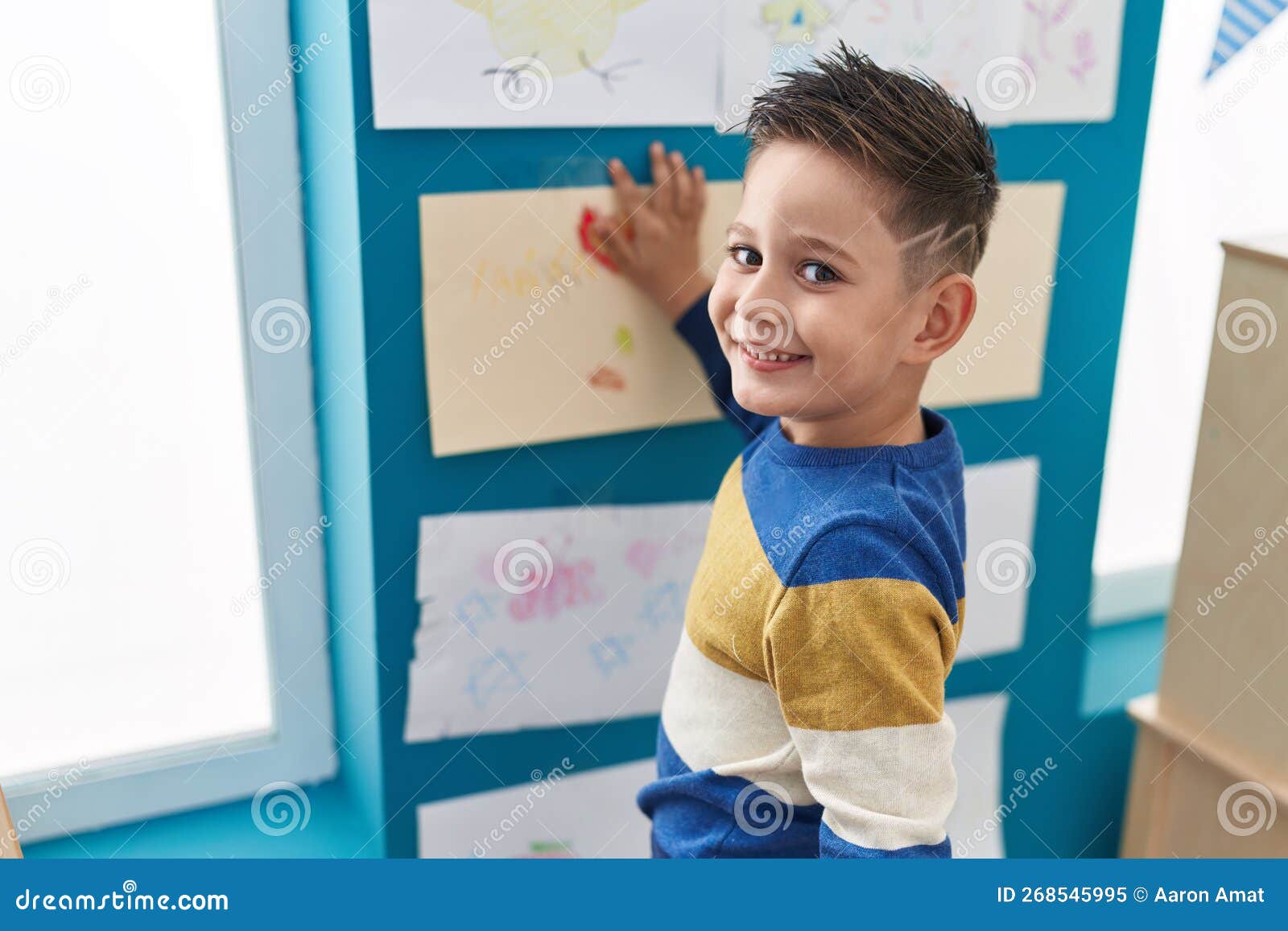 Adorable Hispanic Boy Preschool Student Hanging Draw on Wall at ...