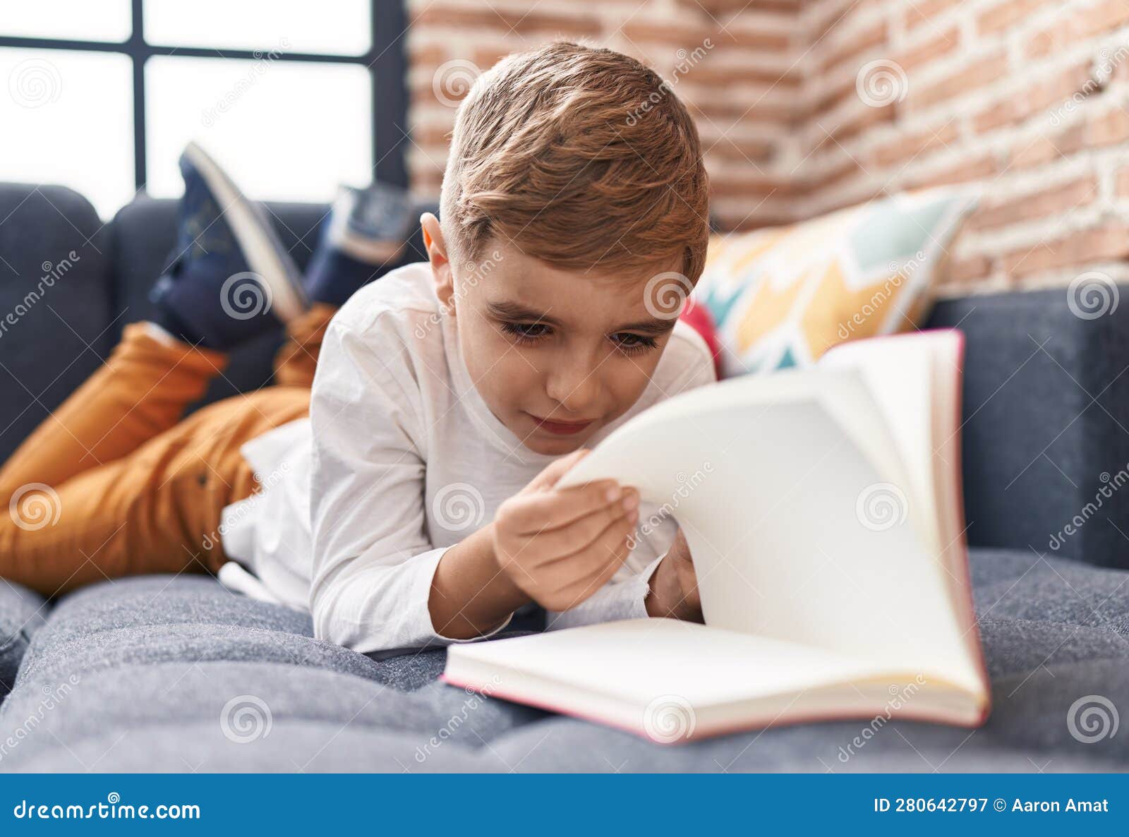Adorable Hispanic Boy Reading Book Lying on Sofa at Home Stock Image ...