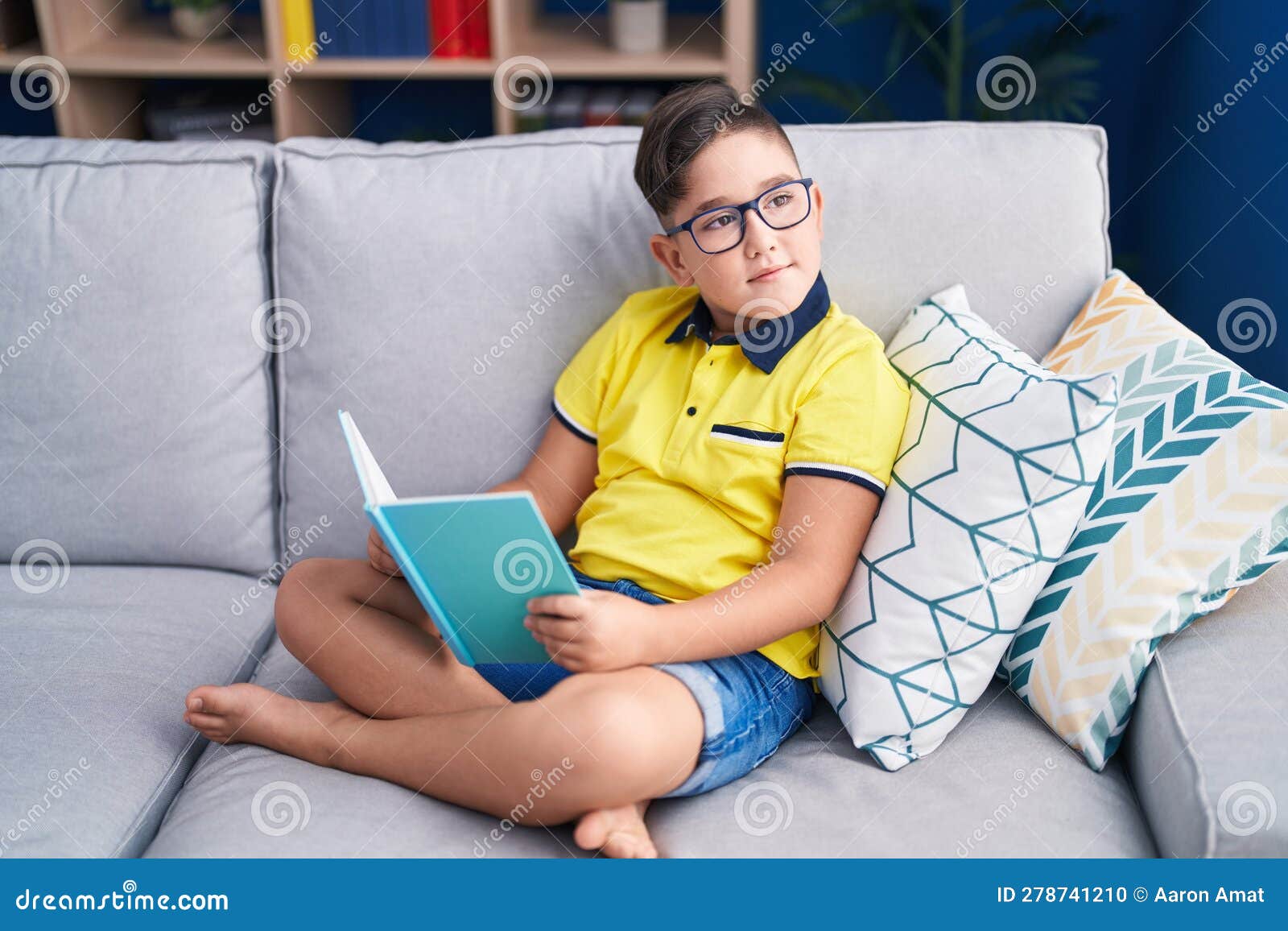 Adorable Hispanic Boy Reading Book Sitting on Sofa at Home Stock Photo ...