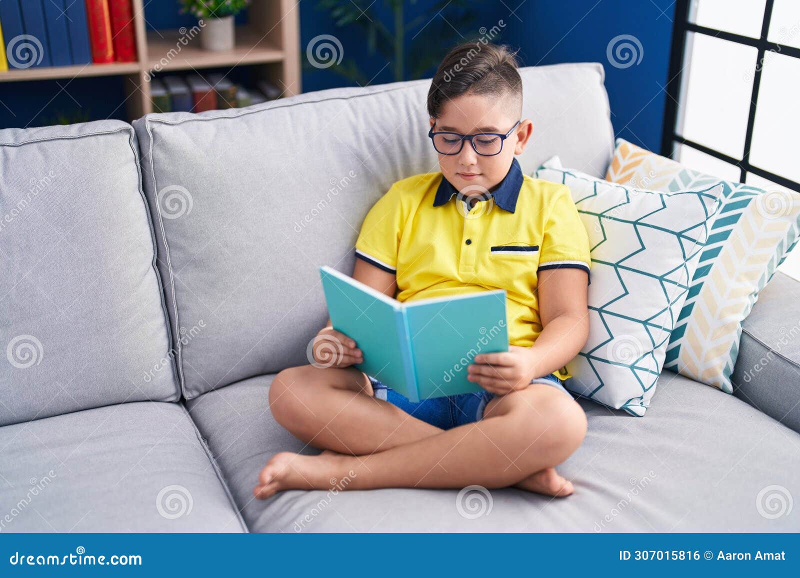 Adorable Hispanic Boy Reading Book Sitting on Sofa at Home Stock Photo ...