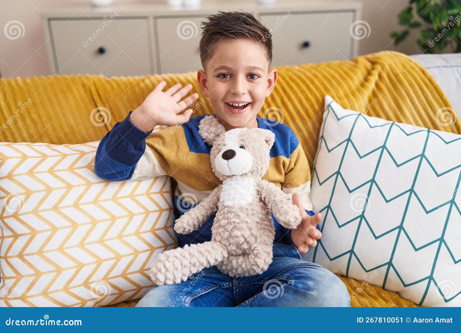 Adorable Hispanic Boy Saying Hello with Hand Sitting on Sofa at Home ...