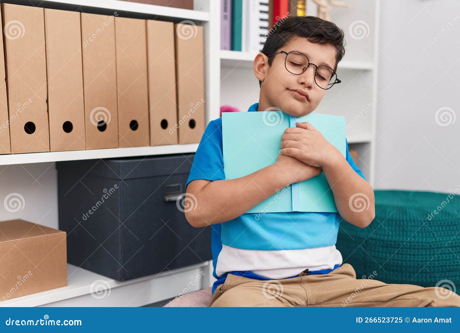 Adorable Hispanic Boy Student Hugging Book at Library School Stock ...