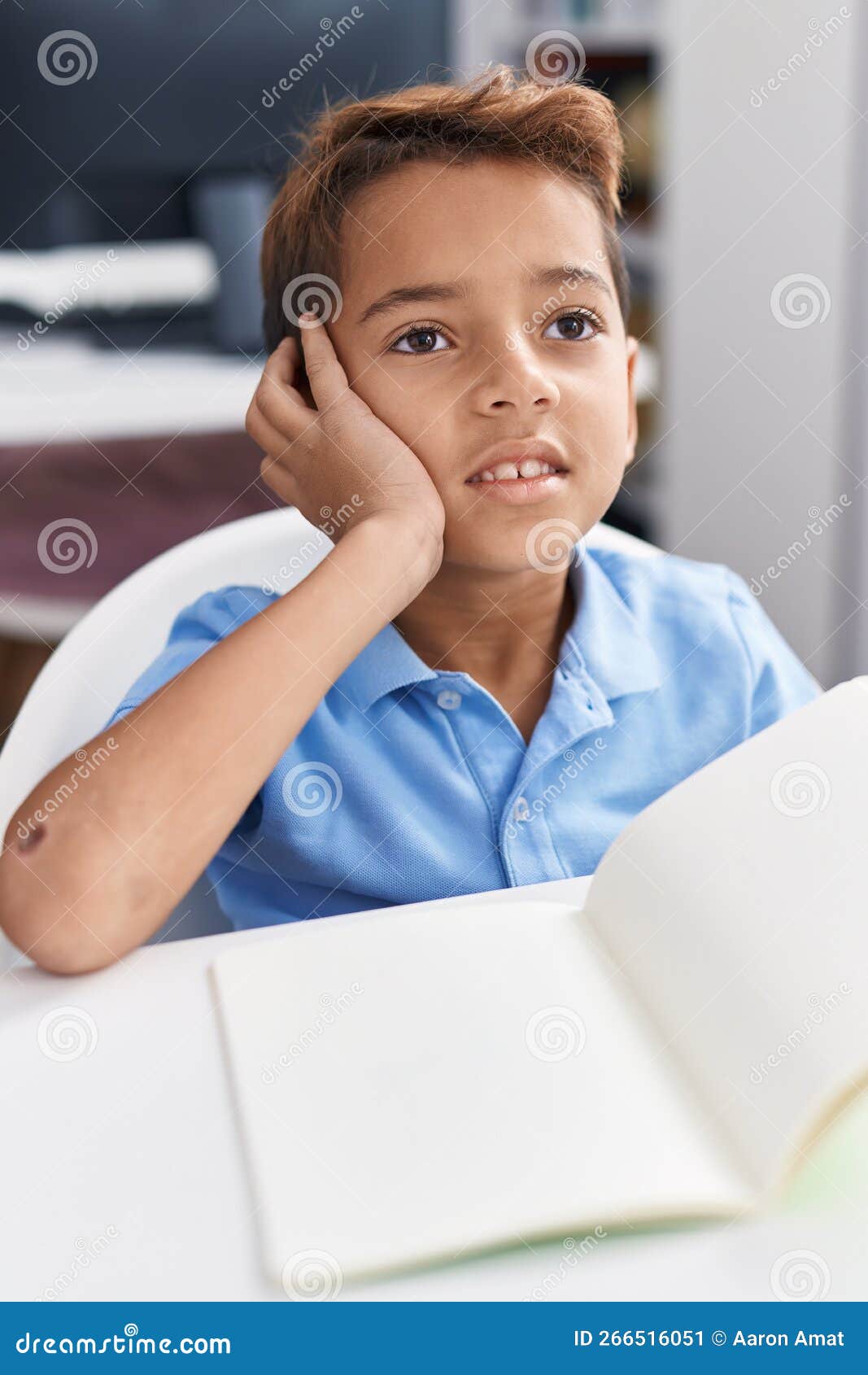 Adorable Hispanic Boy Student Reading Book Thinking at Classroom Stock ...