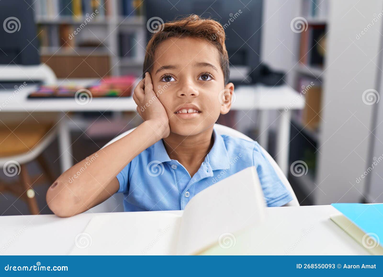 Adorable Hispanic Boy Student Reading Book Thinking at Classroom Stock ...