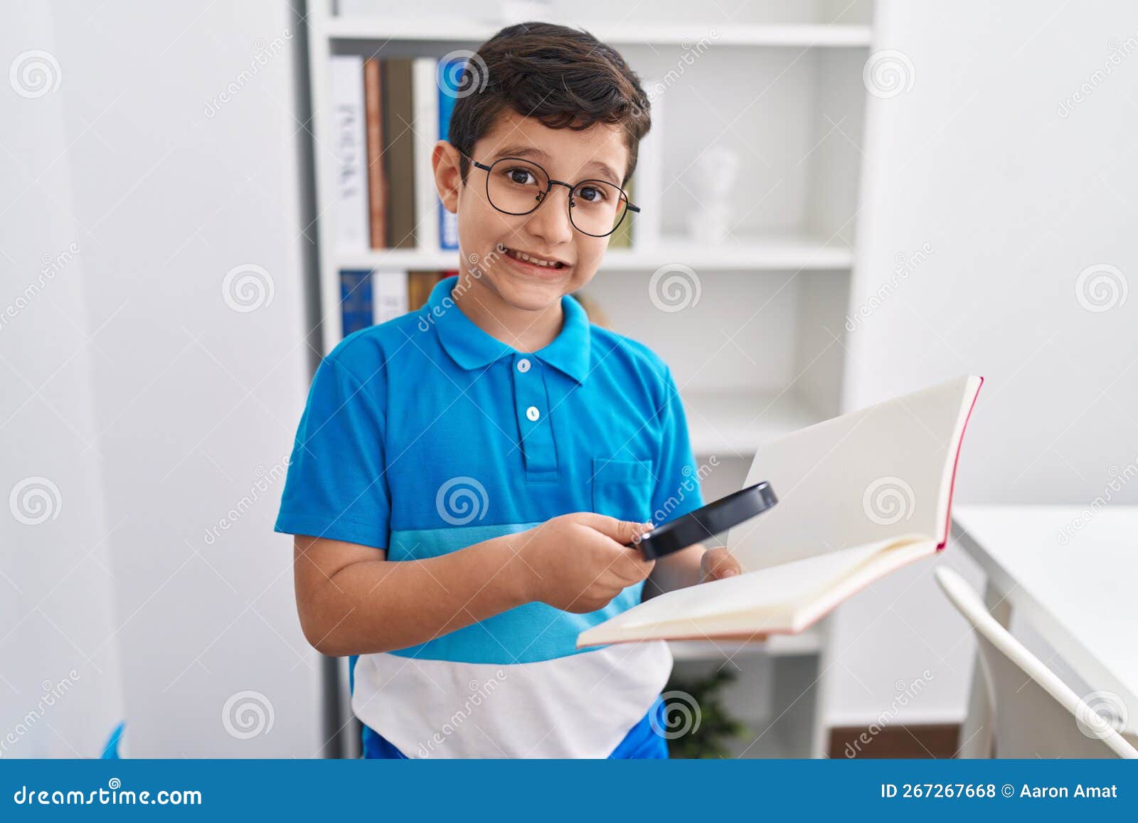 Adorable Hispanic Boy Student Reading Book Using Magnifying Glass at ...